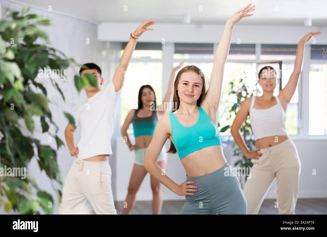 Cheerful teen girl enjoying while training movements of modern group ...