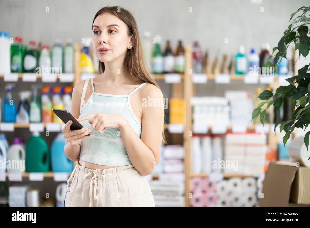 Woman looks at phone screen, scrolling through screen shopping list and ...