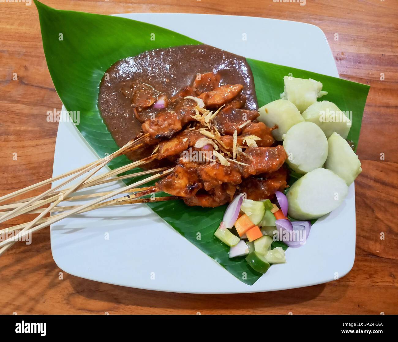 Indonesian Sate Ayam with lontong rice cake served on a banana leaf for ...