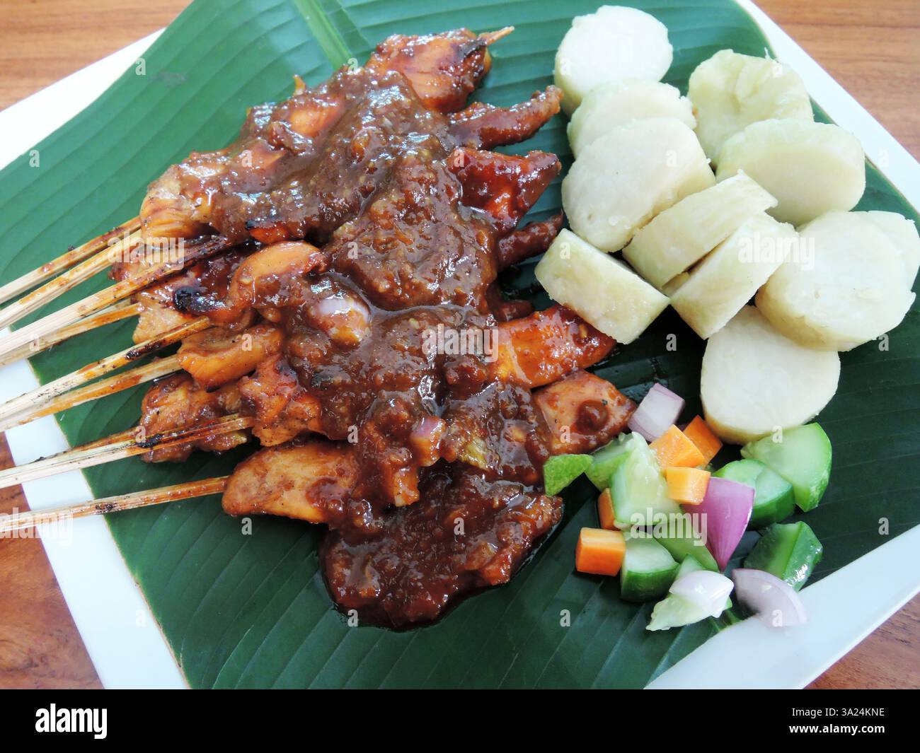 Indonesian Sate Ayam with lontong rice cake served on a banana leaf for ...