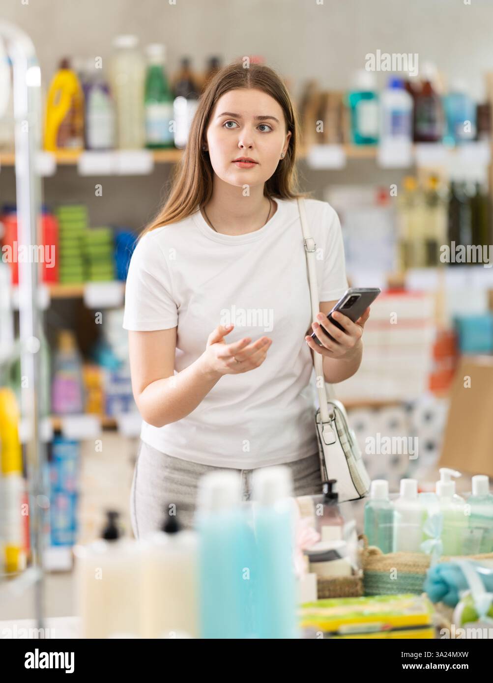 Girl looks at phone screen, scrolling through screen shopping list and ...