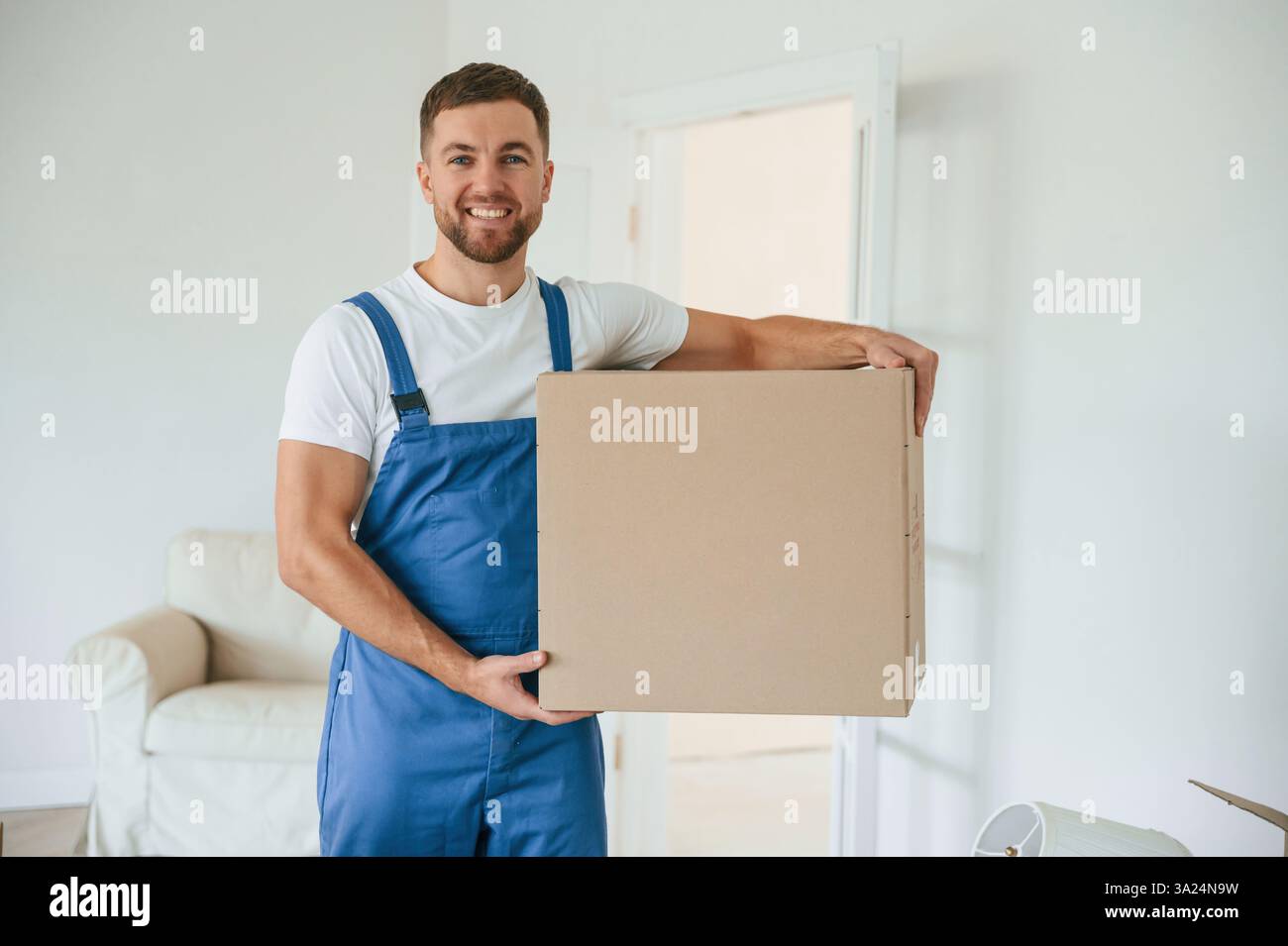 White shirt and blue uniform. With box in hands. Moving service ...