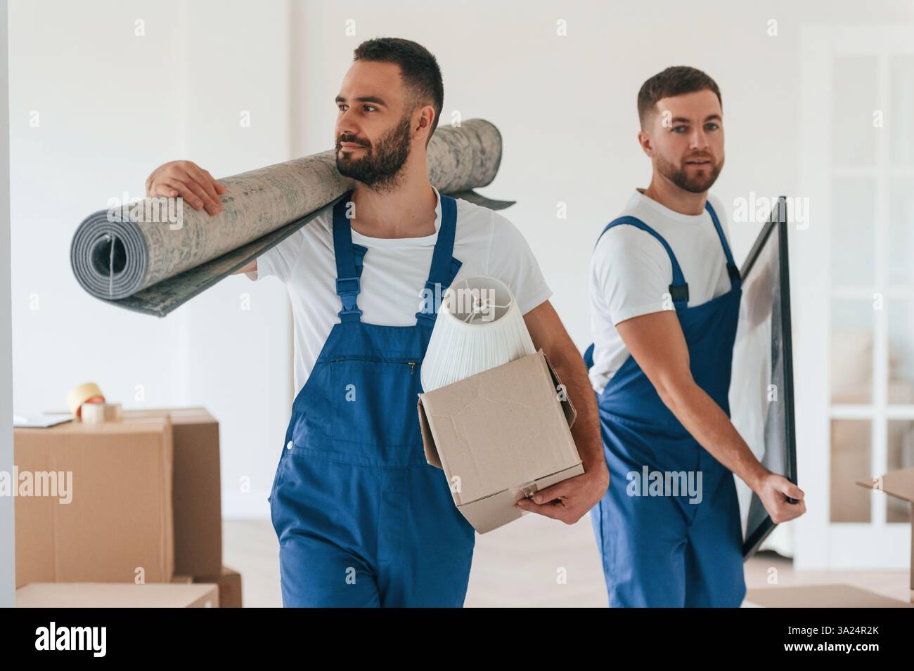 Two moving service employees in a room Stock Photo - Alamy
