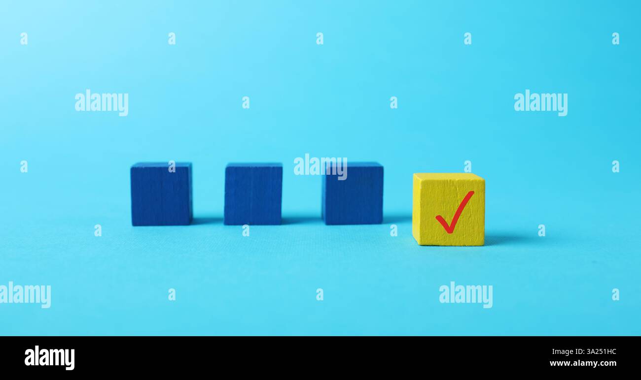 One yellow cube with check mark among others on light blue background Stock Photo - Alamy