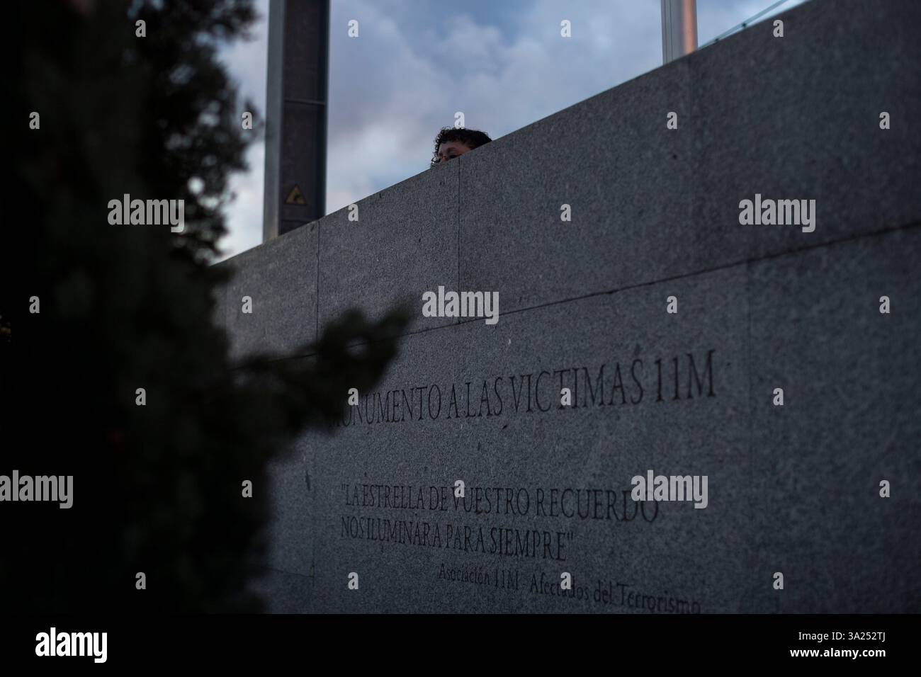 A woman watches the ceremony from behind the wall of the Monument to ...