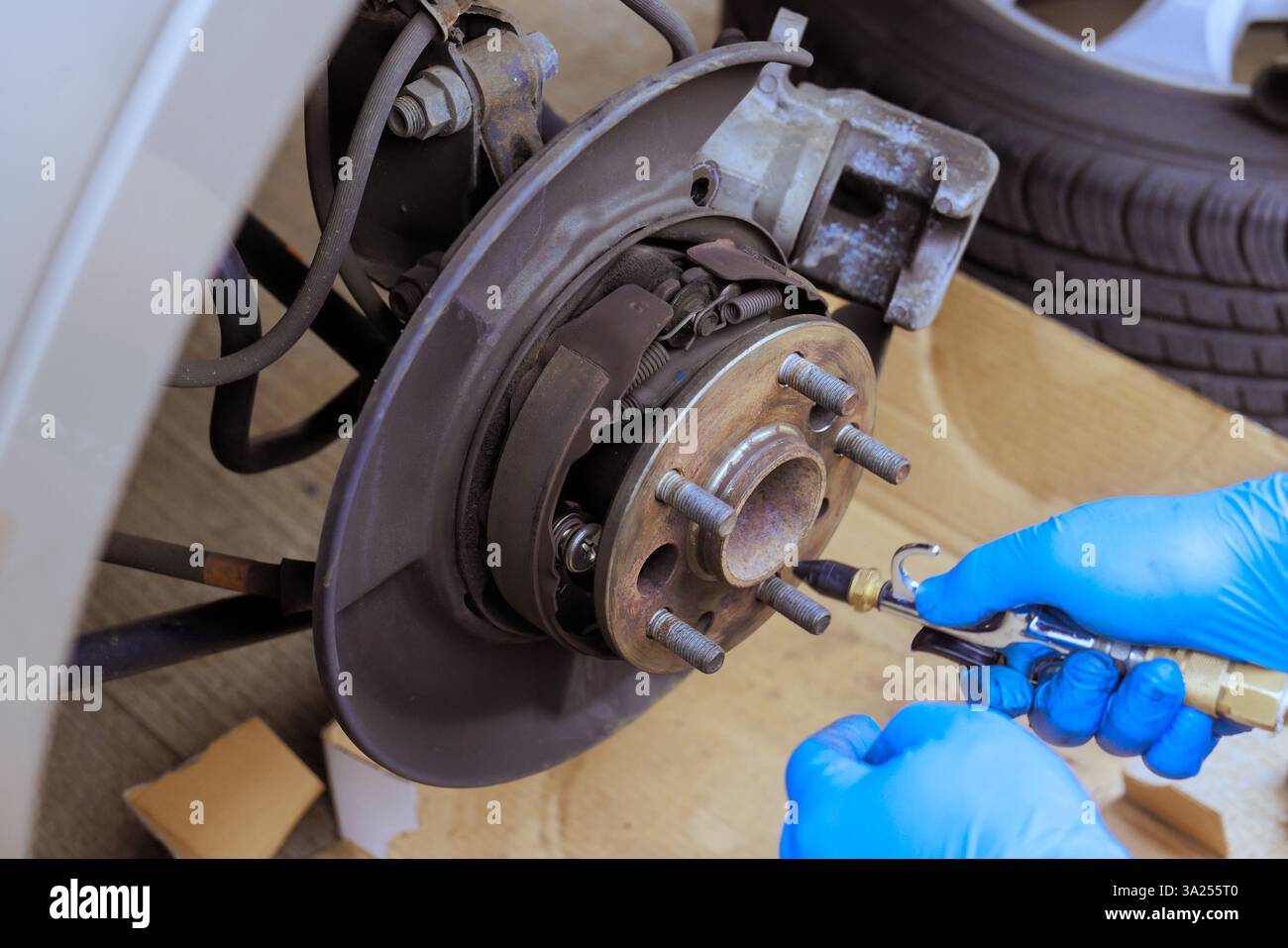 Worker is repairing brake assembly of vehicle in garage, focusing on ...