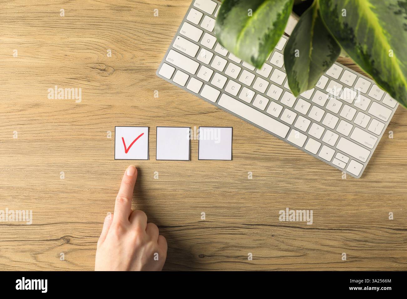 Woman pointing at checkbox with tick mark at wooden table, top view ...