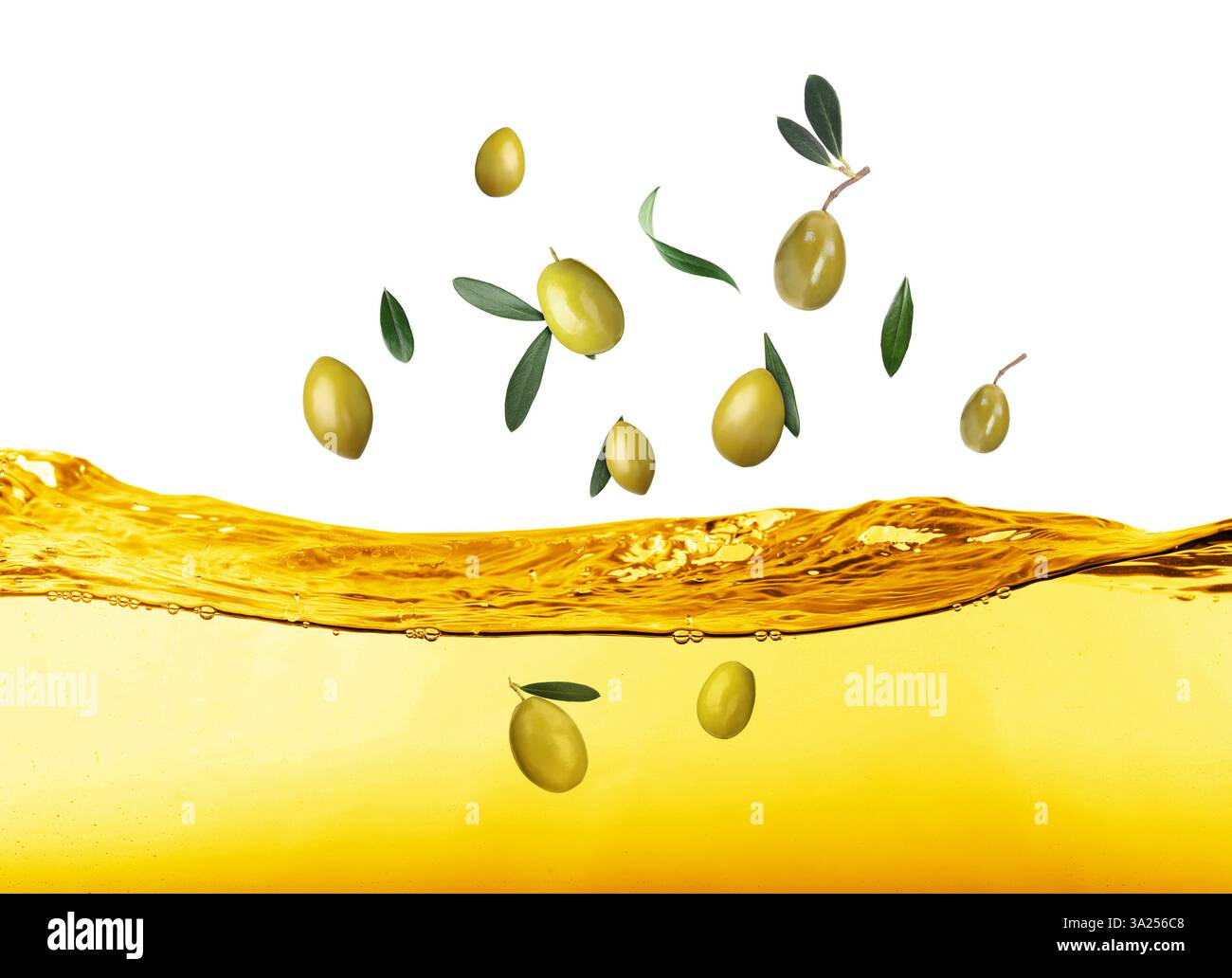 Green olives and leaves falling into cooking oil on white background ...