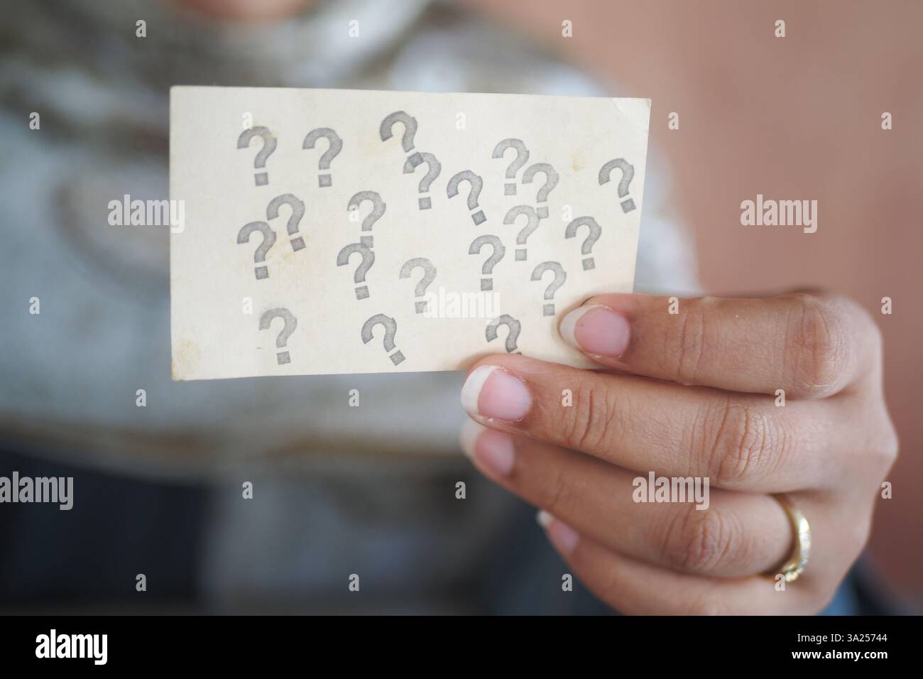 Holding a card with multiple question marks in a thoughtful moment ...