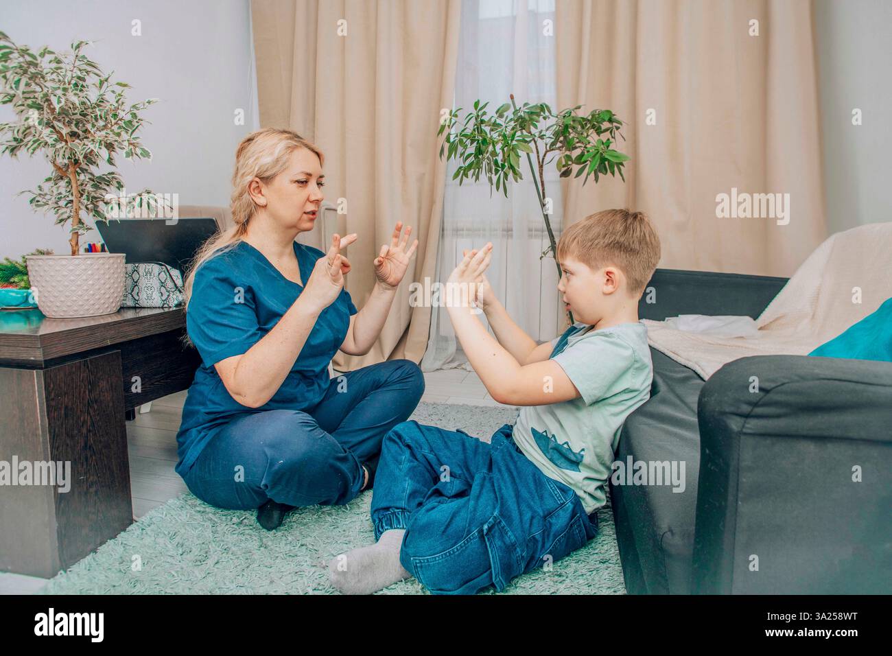 female therapist and boy practicing hand gestures in therapy session ...