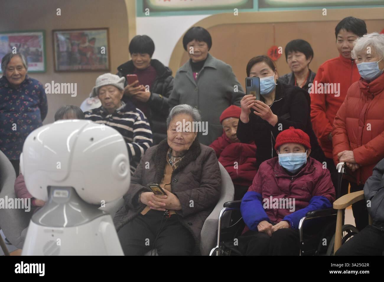 HANGZHOU, CHINA - MARCH 12, 2025 - Elderly people chat with Xiao Xi, an ...