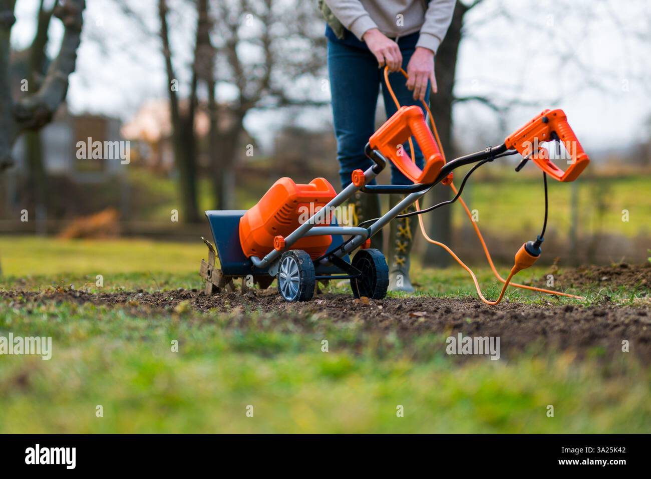 Woman preparing garden beds for planting. Rotavator, garden tiller ...