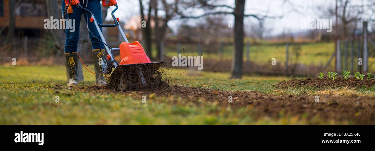 Gardener tilling garden beds for planting. Rotovator, garden tiller or ...