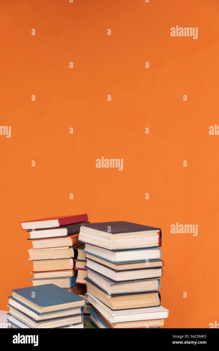 Stacks of old books on an orange university background Stock Photo - Alamy