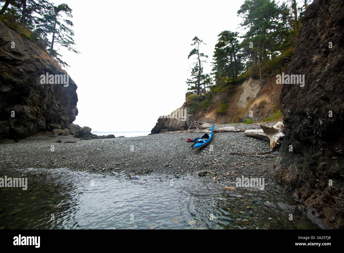 Sea kayak on a beach at Deception Pass State Park, cliffs, pebble ...