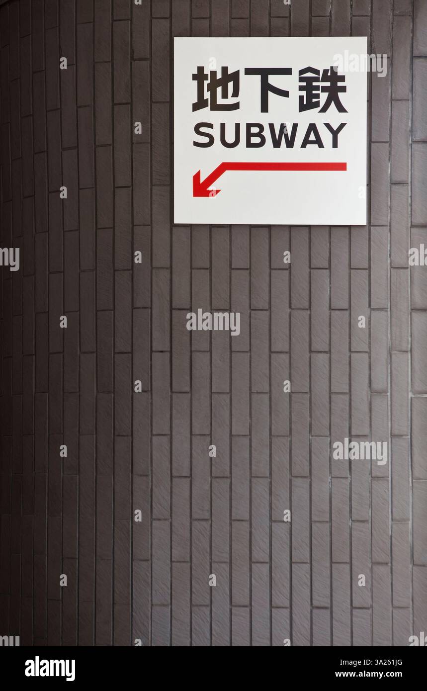 Subway entrance sign and red arrow in Western script and Japanese ...