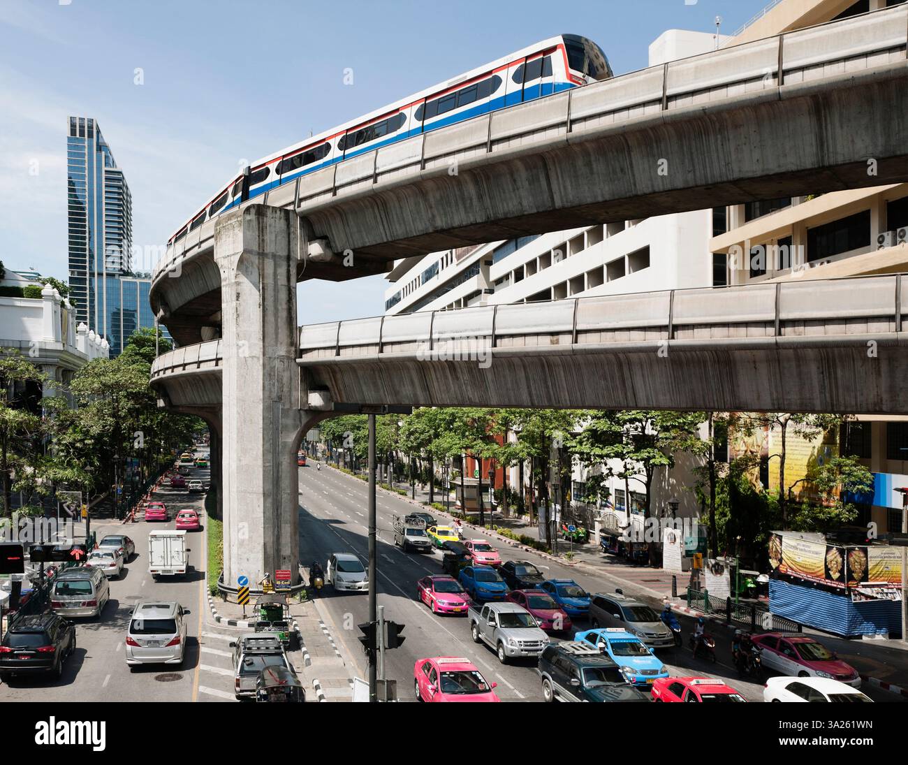 A mass transit train travelling on an elevated track above a busy city ...