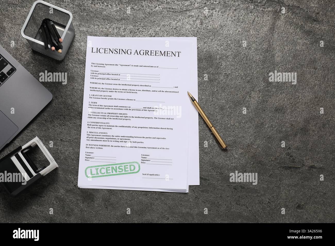 Licensing agreement document, laptop, stamp, pen and pencils on gray ...