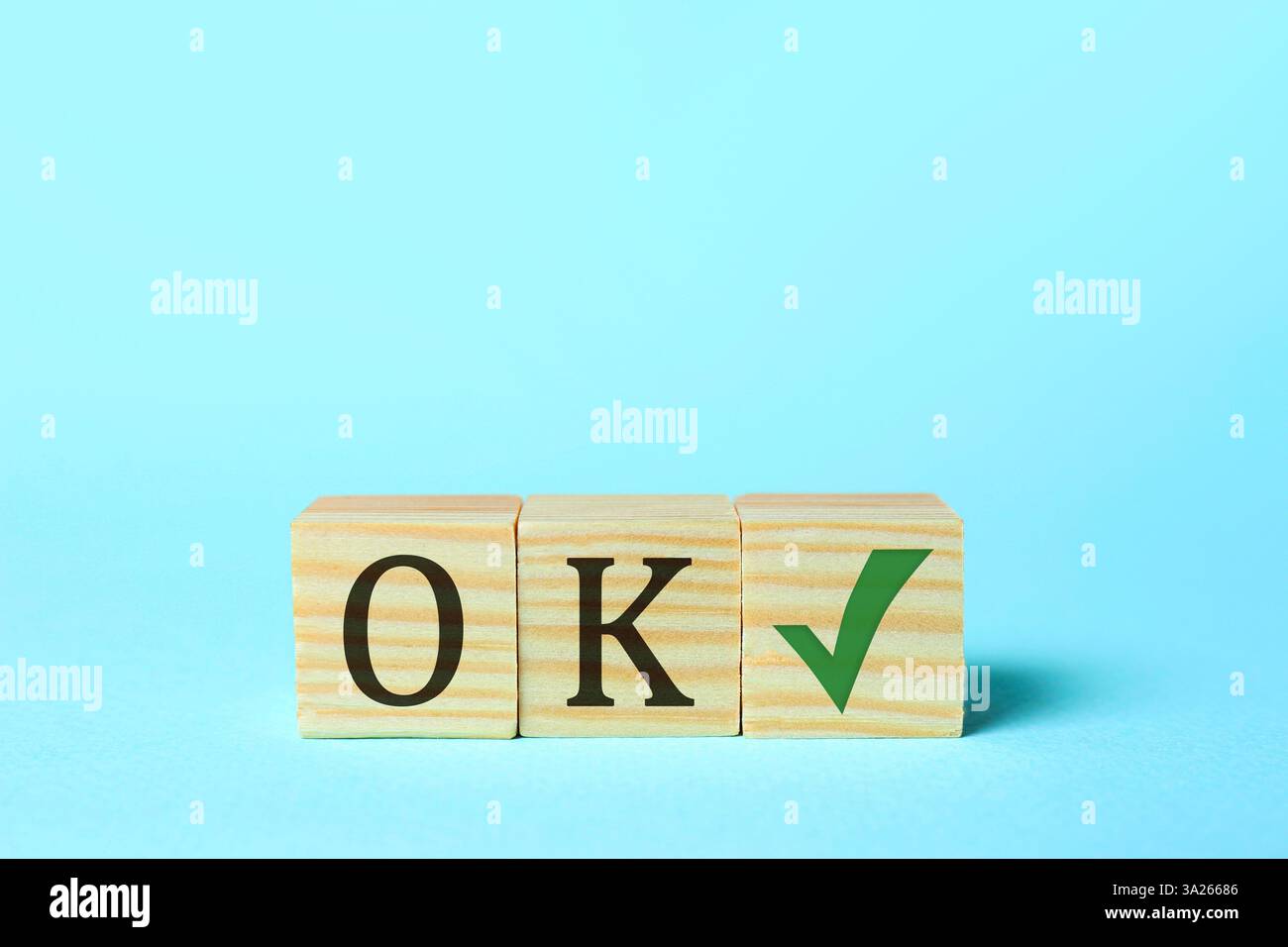 Wooden cubes with abbreviation OK and check mark on light blue ...