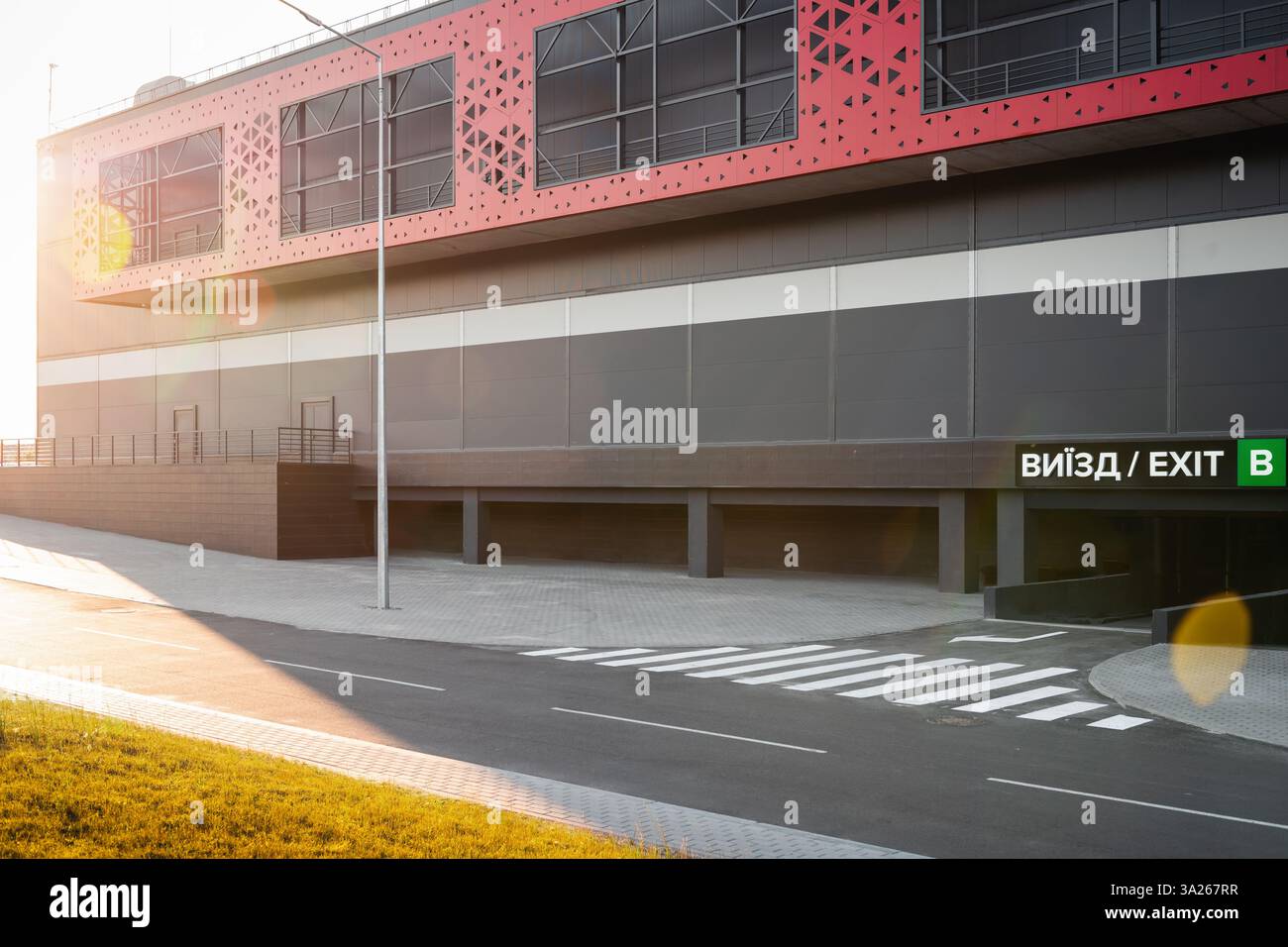 Parking garage exit gate, big building. Empty street along striped red ...