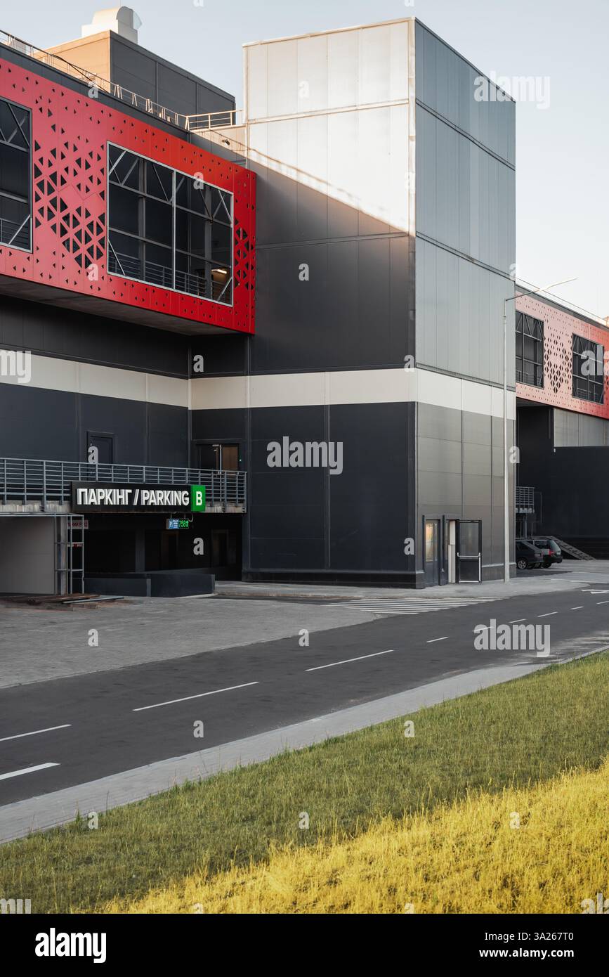 Parking garage exterior, big grey building with red decorative elements. Empty urban street at ...
