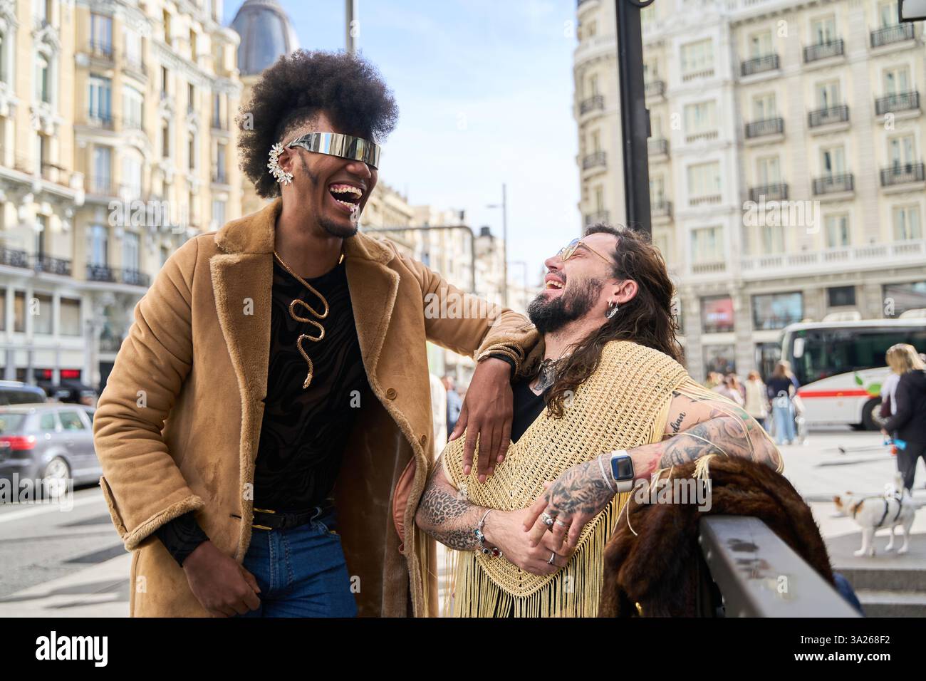 Two stylish men, embracing and laughing, enjoy a carefree moment ...