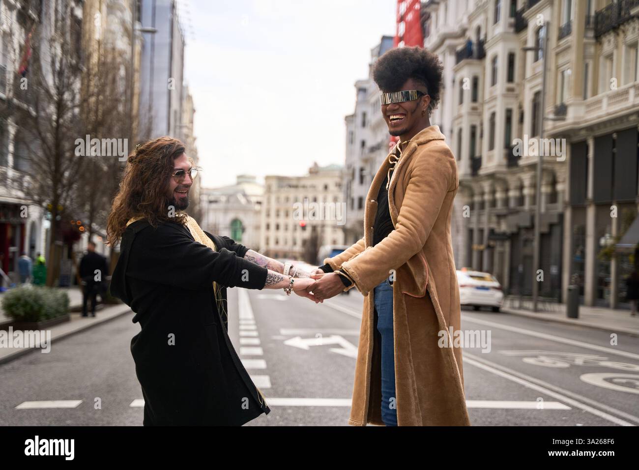 Two androgynous non binary people holding hands and smiling while ...