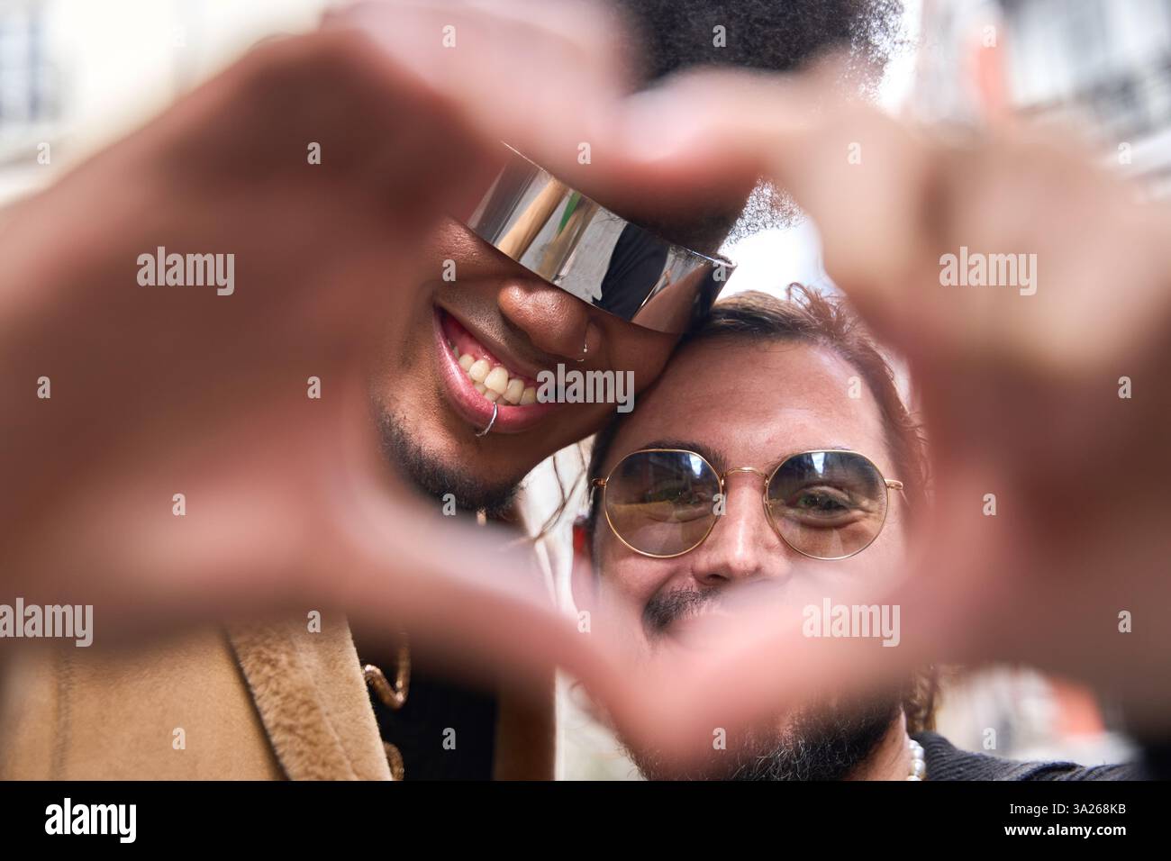 Two androgynous men forming a heart shape with their hands, celebrating ...