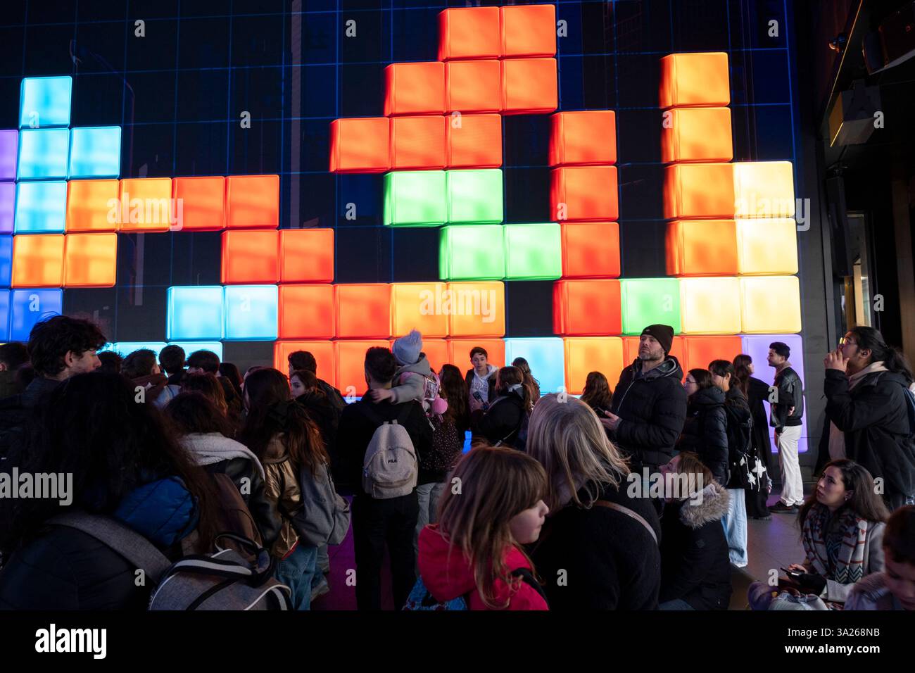 People interact with large scale digital screens displaying a giant ...
