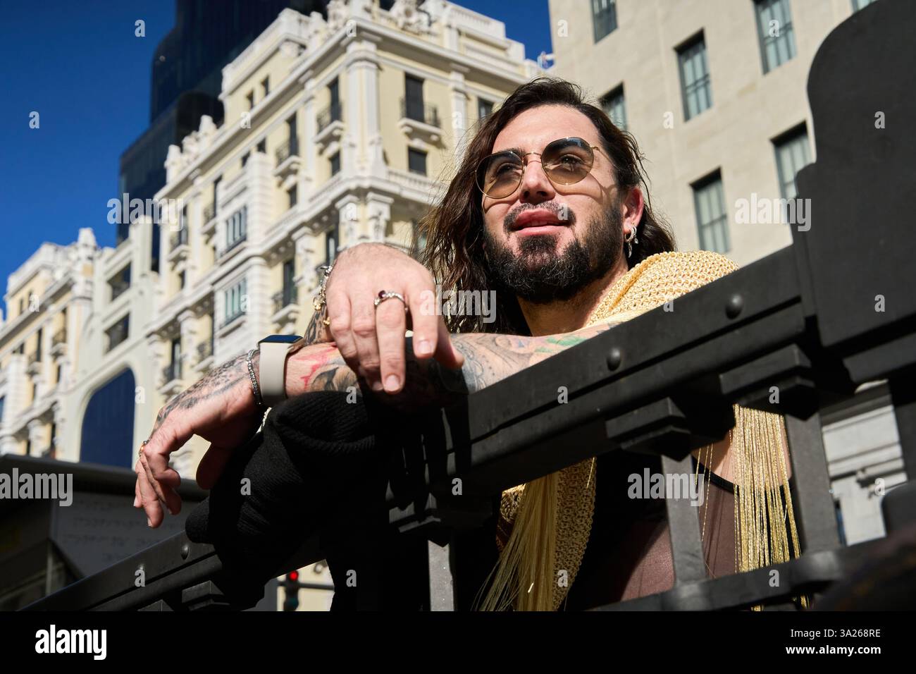 Happy non binary LGBTQ male with tattoos and long hair leaning on a ...