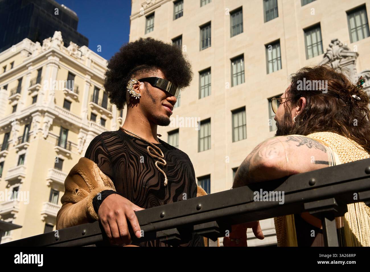 Two androgynous non binary people wearing fashionable clothing are ...