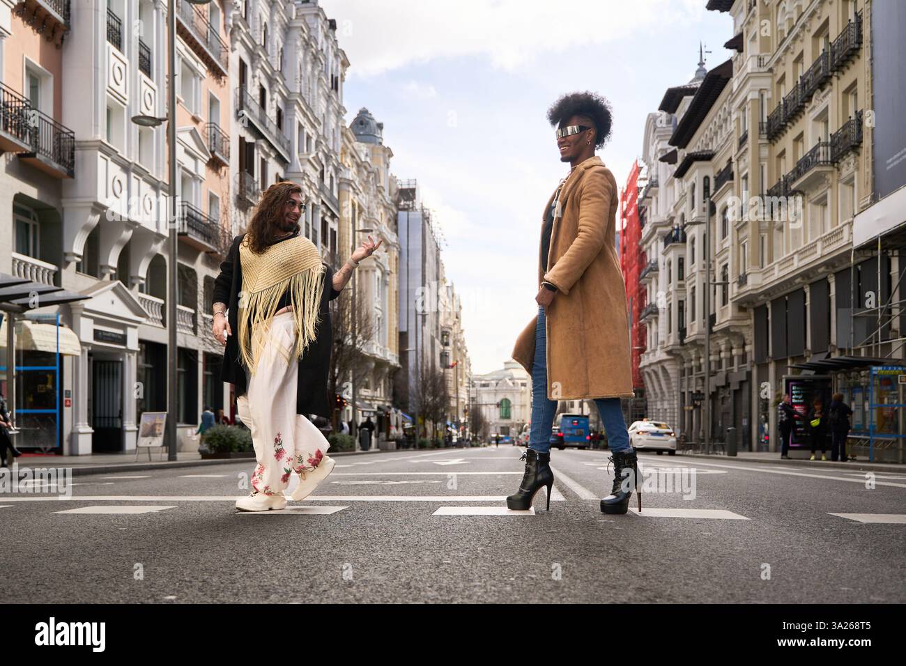 Two androgynous people are crossing the street in a big city ...