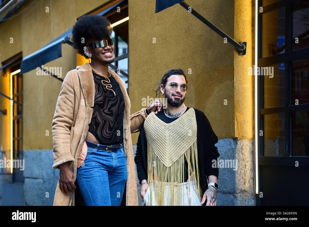 Two androgynous non binary people walking and smiling in the city ...