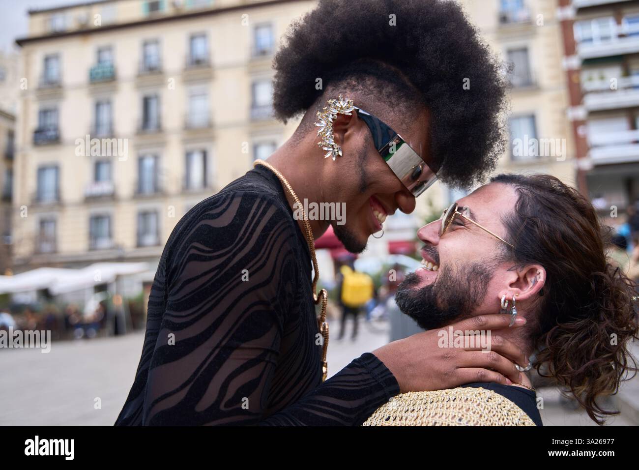 Two androgynous non binary people embracing and smiling in a city ...