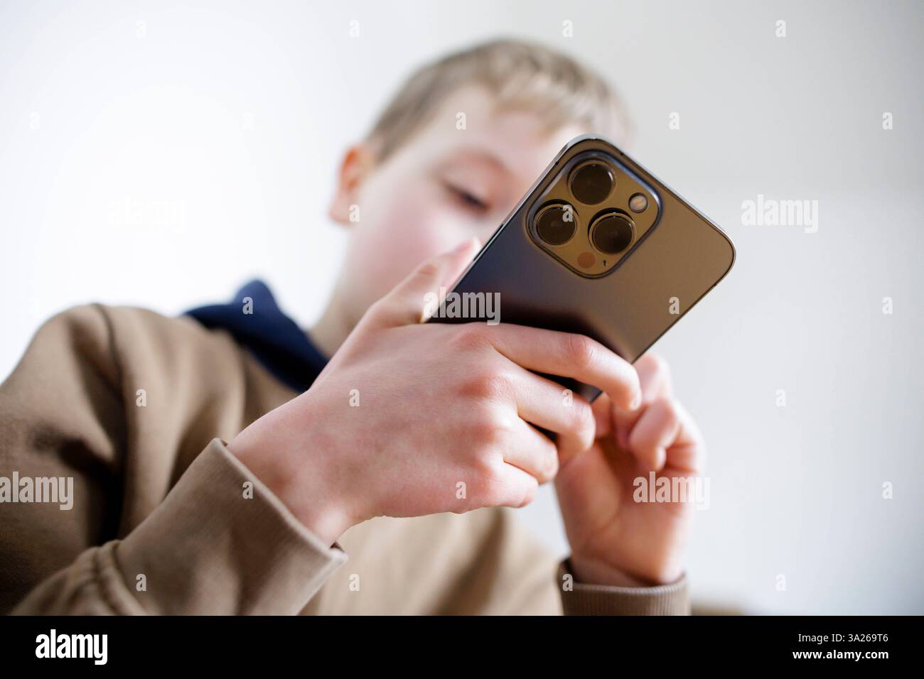 Symbolfoto zum Thema Handynutzung von Kindern. Ein Junge haelt ein ...
