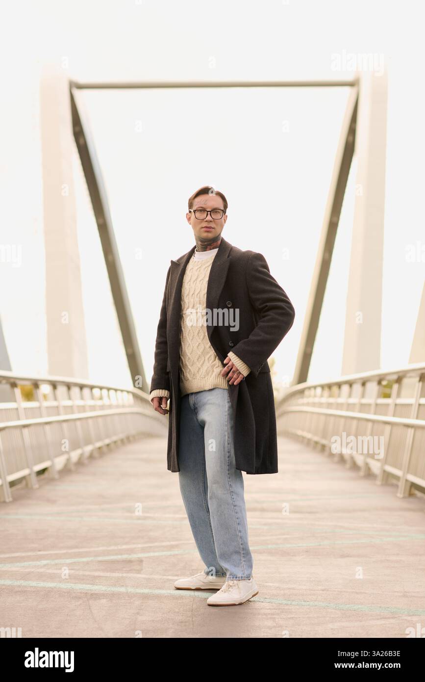 Handsome man in a chic outfit showcases his tattoos while standing on a ...