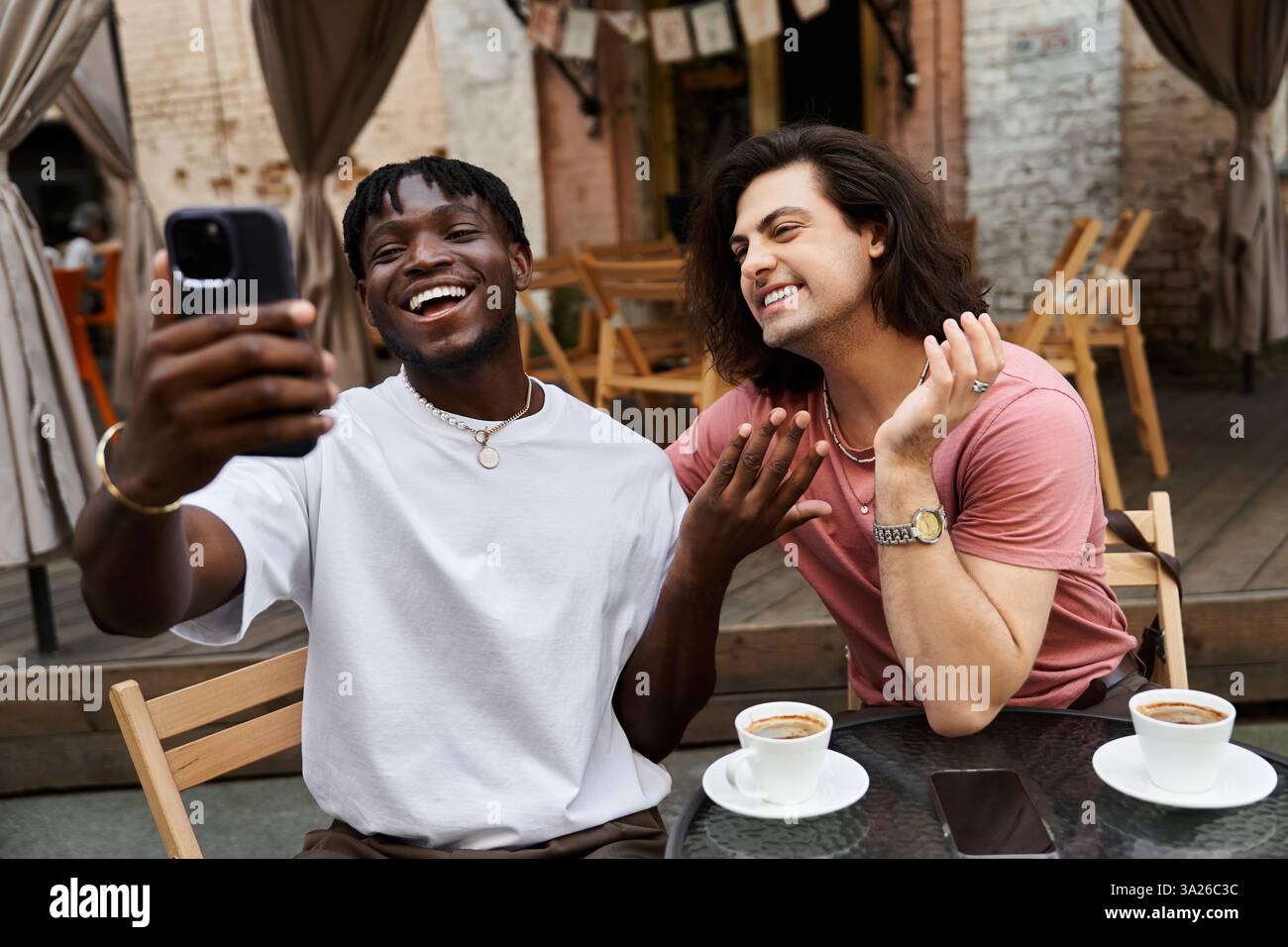 Two handsome men laugh together while taking a selfie during their ...