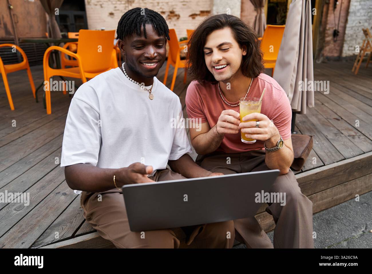 A couple shares a cozy cafe moment, laughing over drinks and a laptop ...