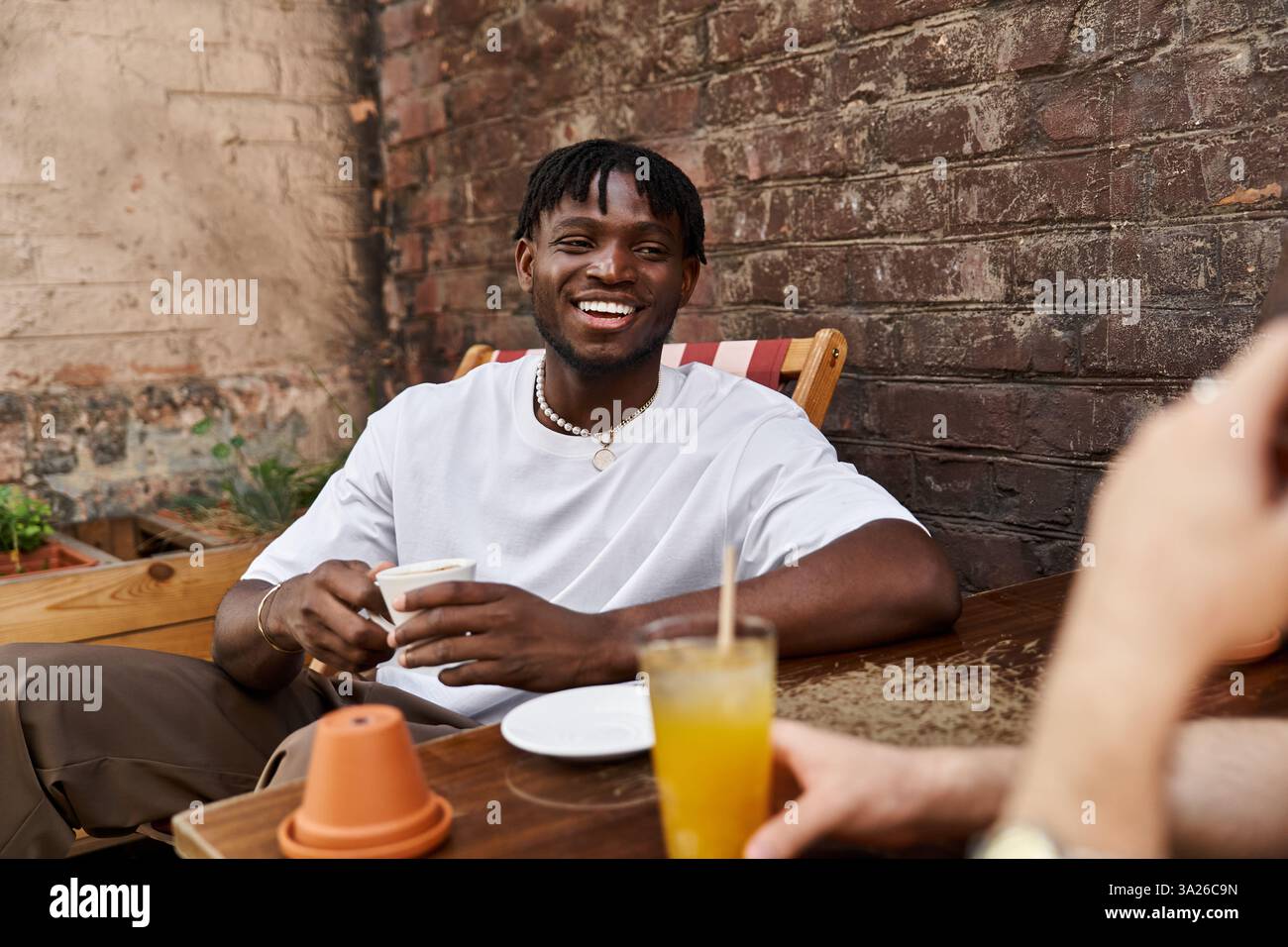 Two handsome men share laughs and drinks at a rustic cafe table in a ...