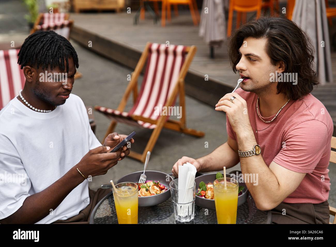 Two handsome men share a delightful meal, engaging in conversation and ...