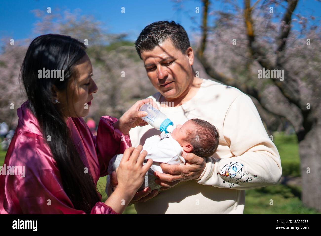 Loving parents nurturing their newborn baby with a bottle of milk ...