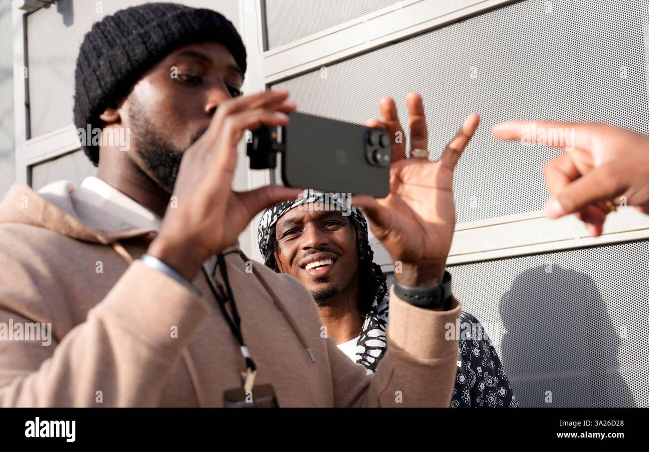 Retired NFL player T.J. Wright, center, watches footage on NFL player Charles Harris' phone as ...