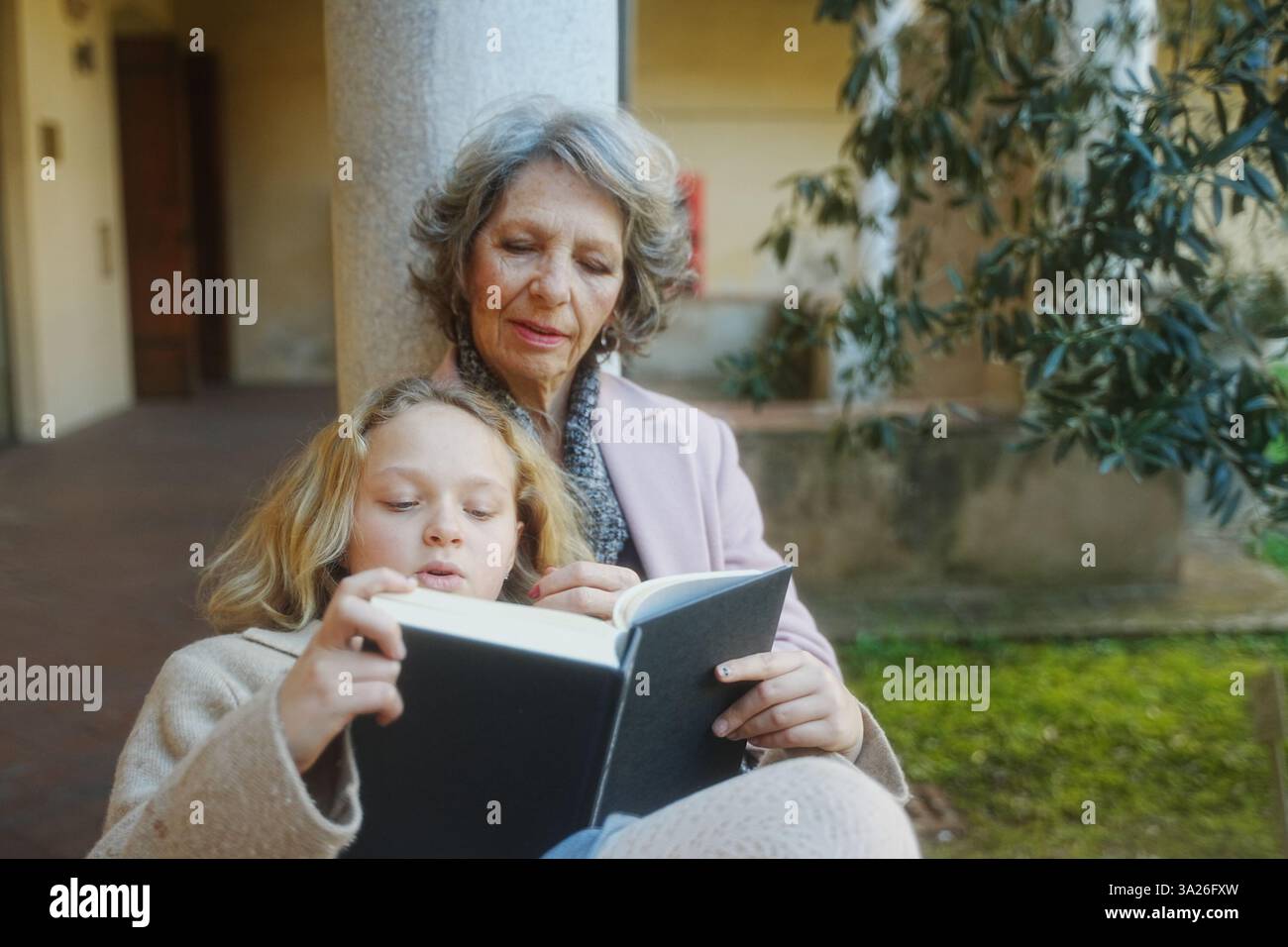 Spring. Grandmother and granddaughter reading a book in the library ...