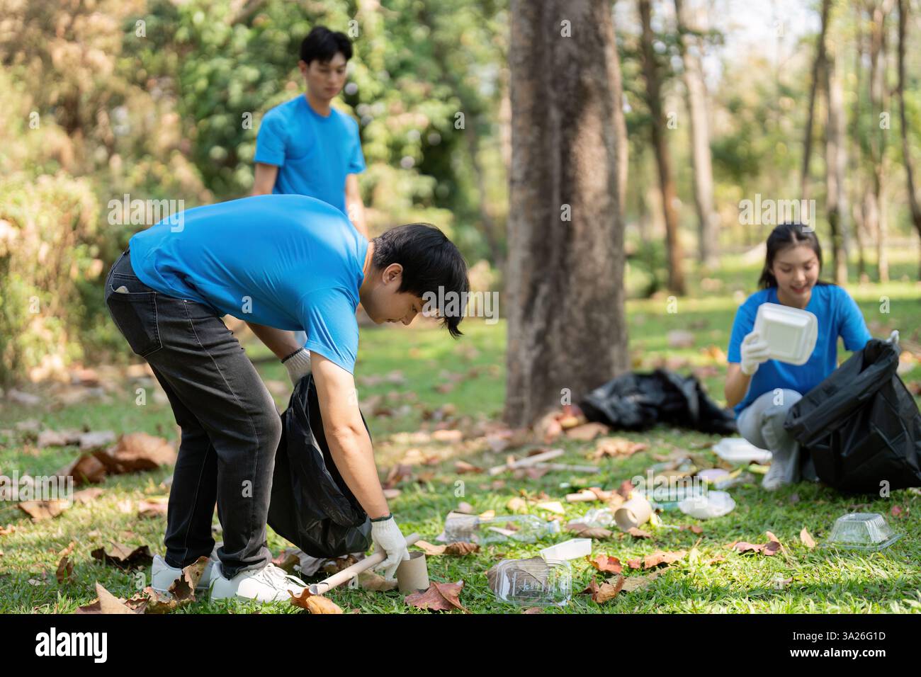 Dedicated volunteers. Young people focused on park cleanup tasks Stock Photo - Alamy