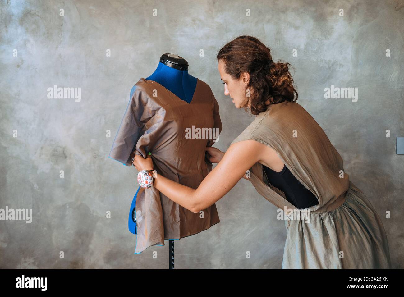 Fashion designer standing next to mannequin, creating dress from piece ...