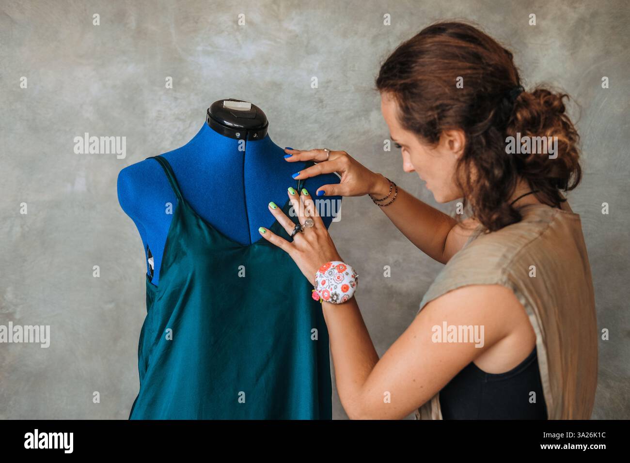 Portrait of woman fashion designer standing next to mannequin adjusting ...