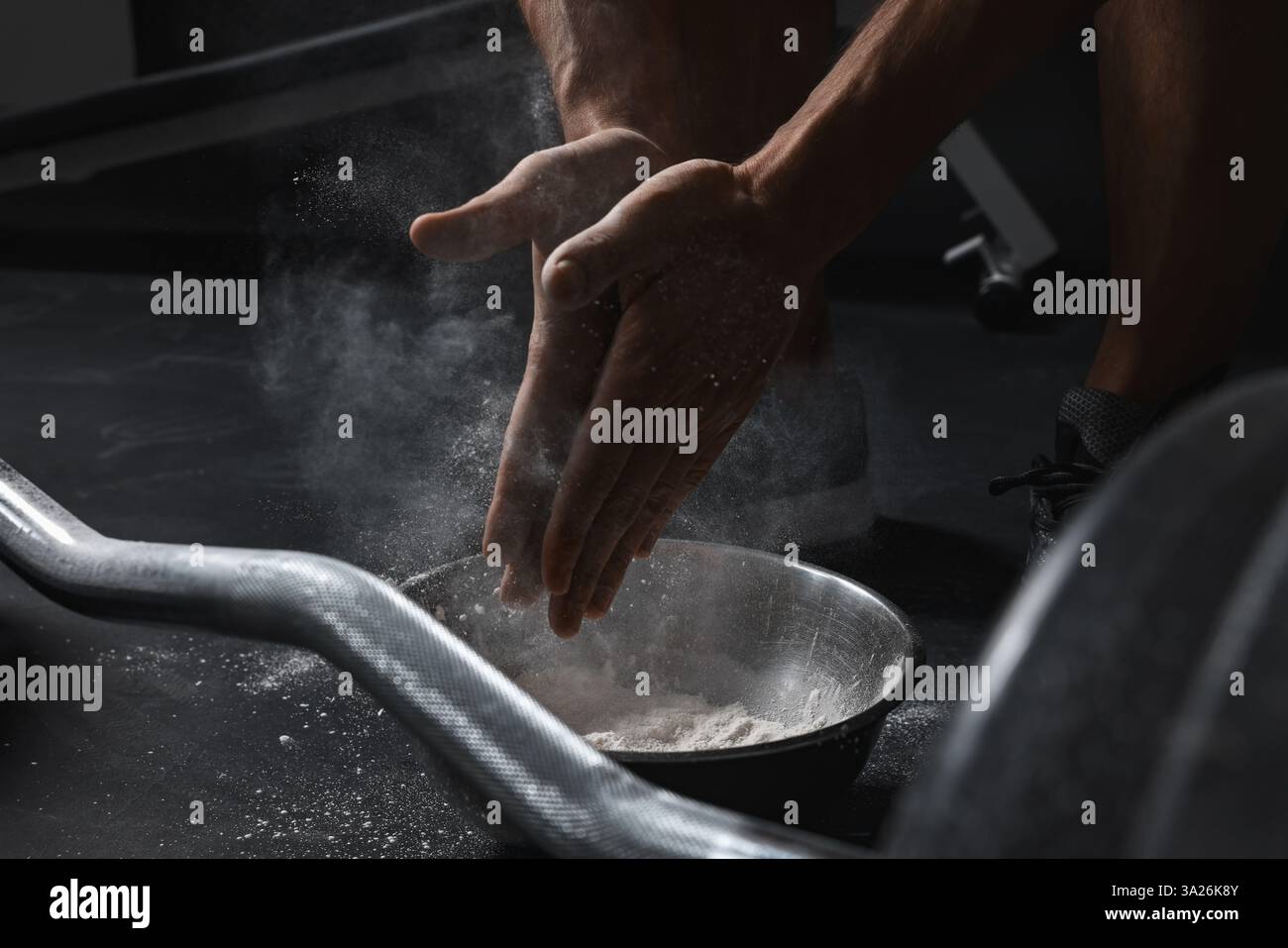 Man clapping hands with talcum powder before training with barbell in ...
