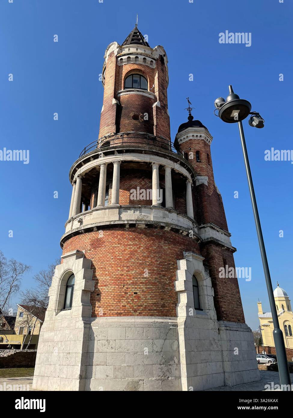 A medieval red-brick tower with white stone accents stands tall under a ...