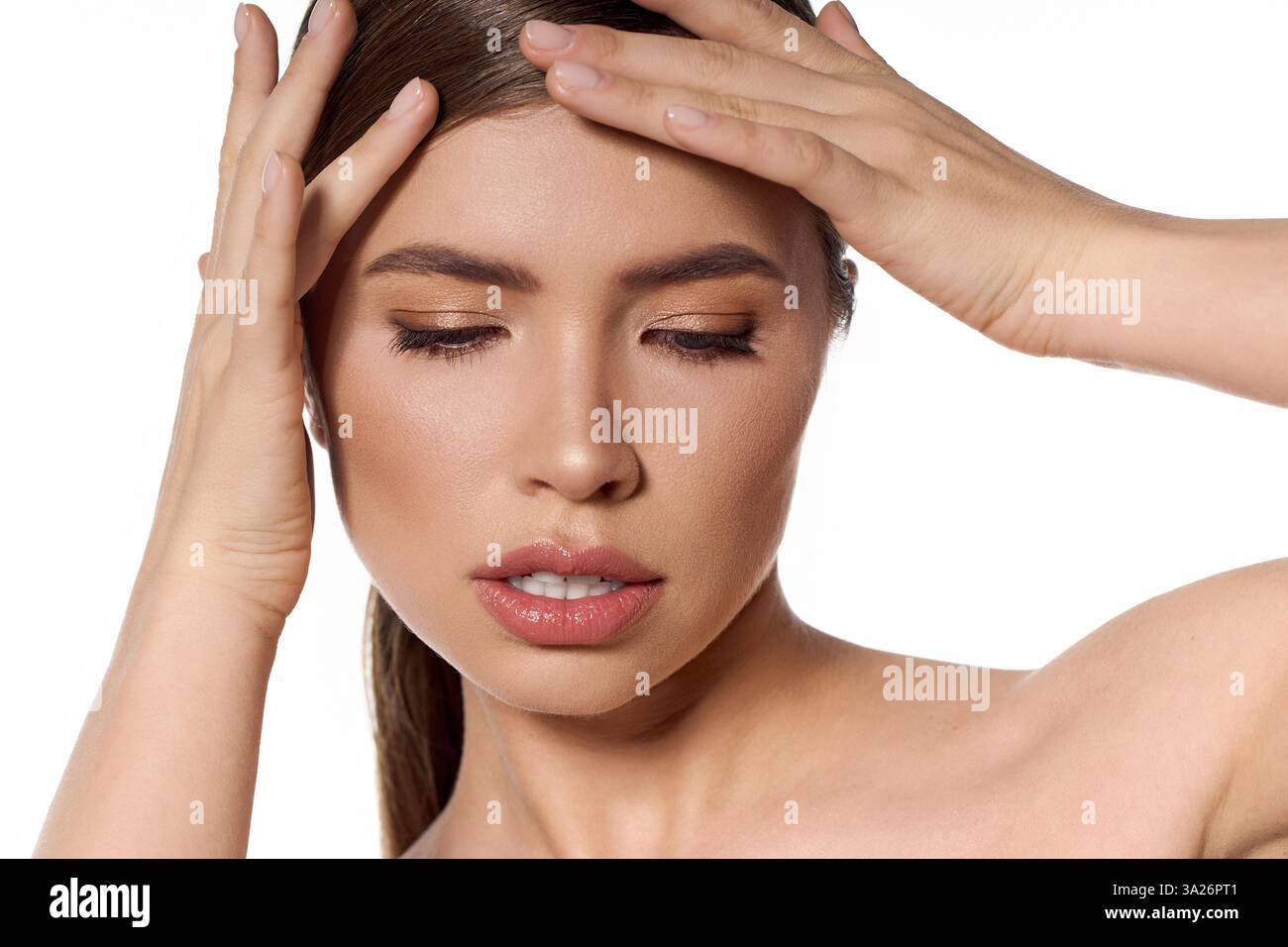 A young, beautiful woman touches her forehead in a reflective moment ...
