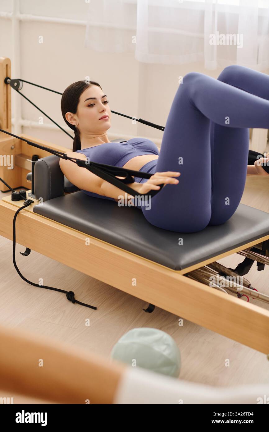 A dedicated individual practices pilates movements on a reformer in an ...
